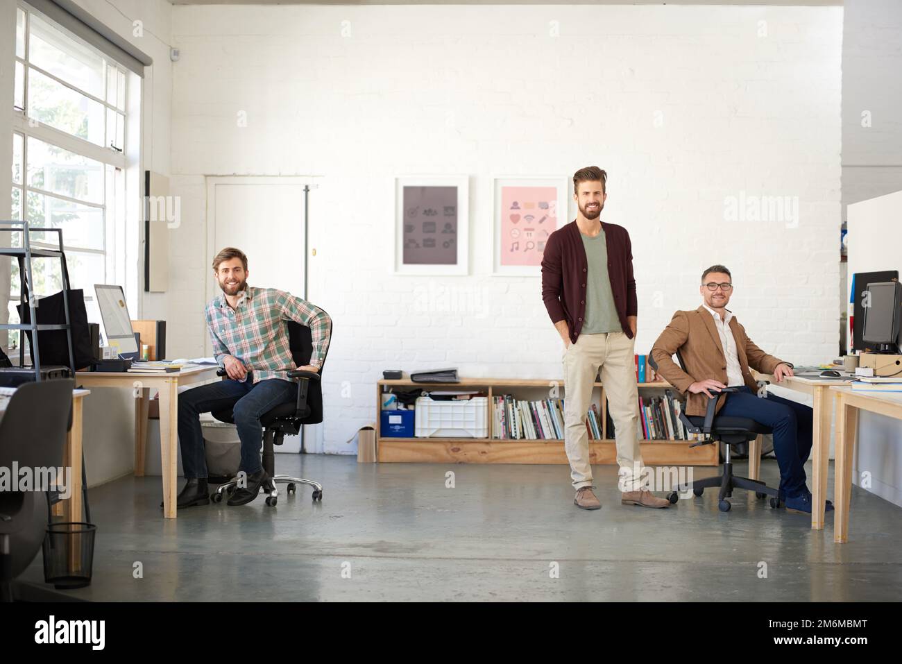 Working as a team gets things done. Open office space with 3 male ...