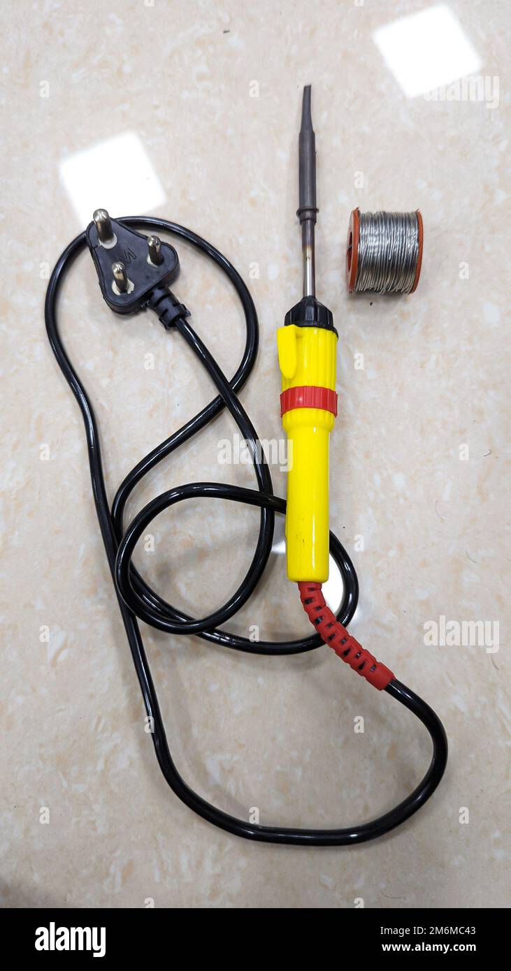an electric soldering tool with plug and solder metal wire on the floor ...