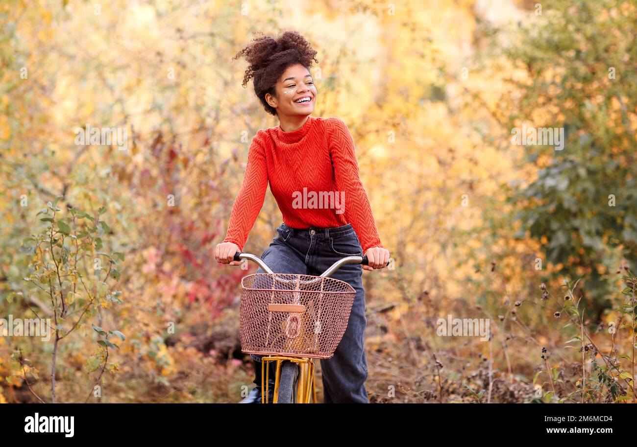 Young happy smiling african american woman riding bicycle in autumn ...