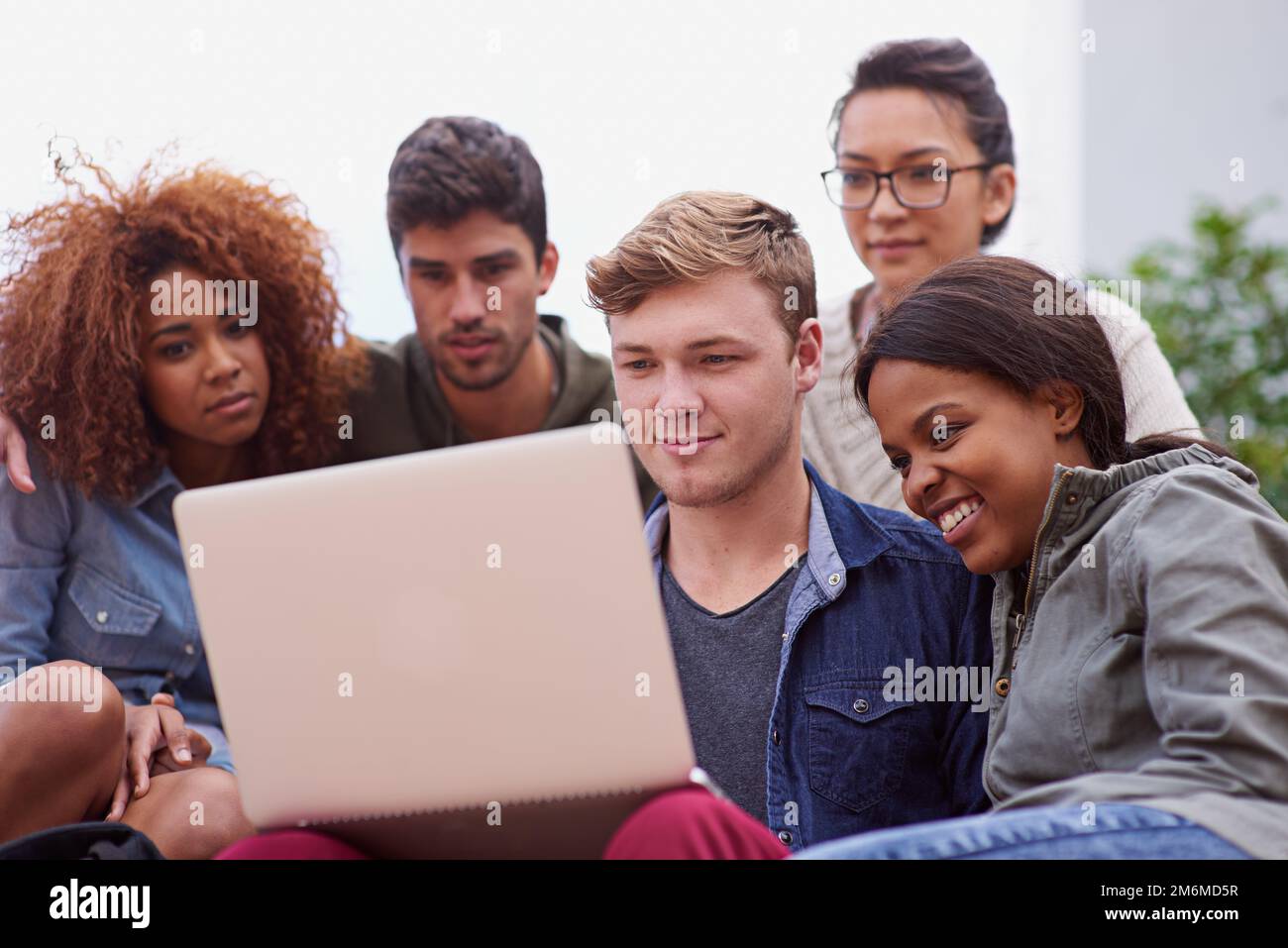 Online group studying. a group of students sitting outside while on ...