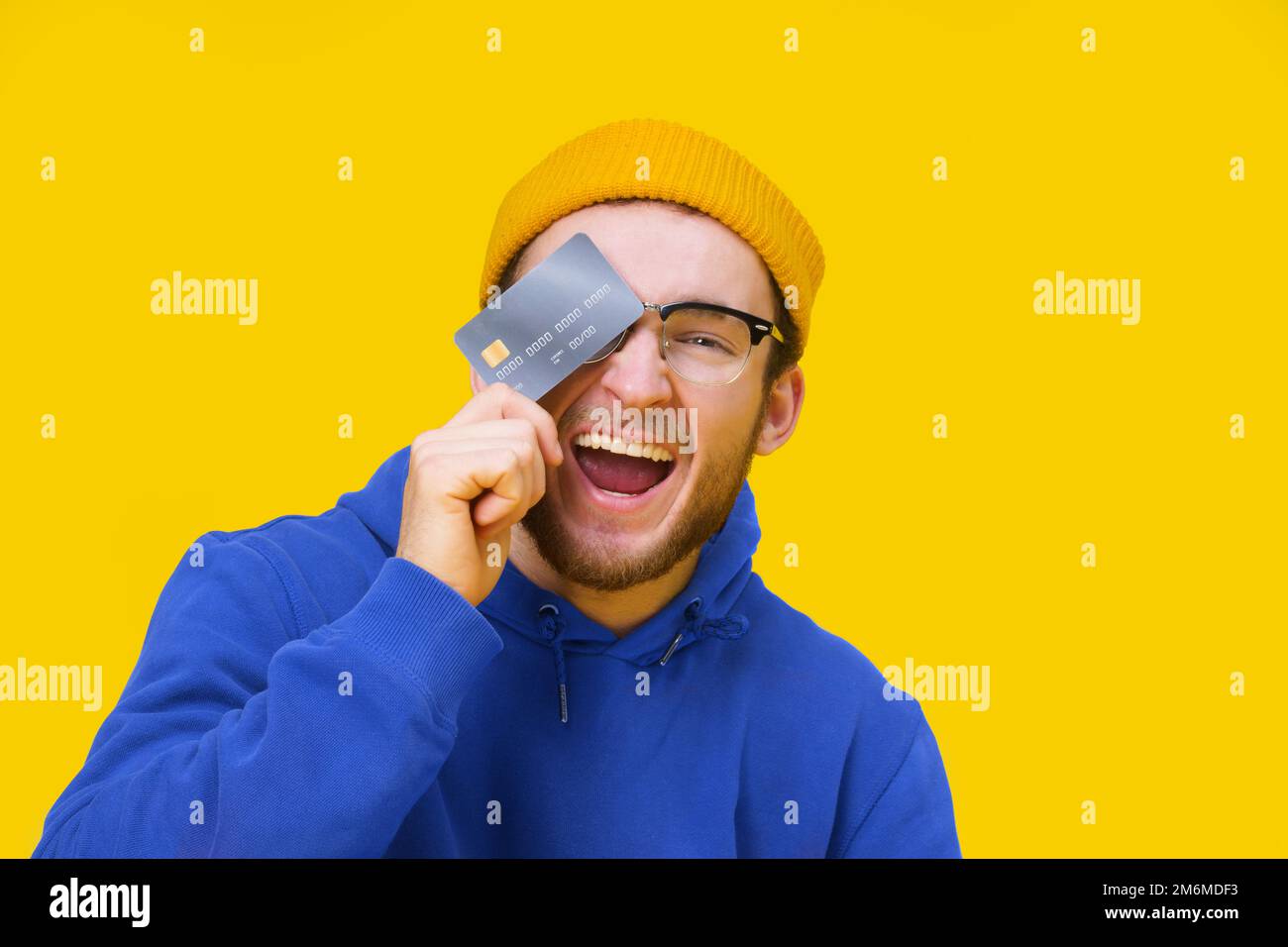 Happy young caucasian guy with credit, debit card in hand smiling cover ...