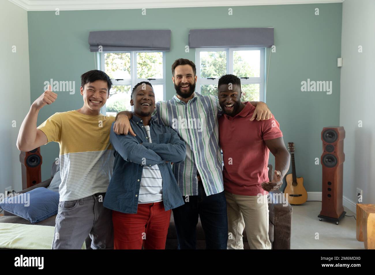 Portrait of cheerful multiracial male friends smiling while standing in ...