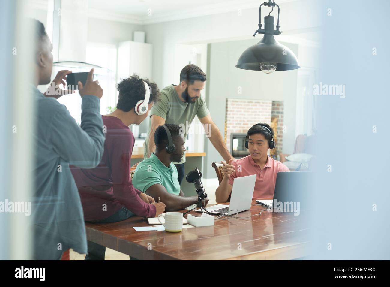 Multiracial male colleagues interviewing and recording podcast and ...