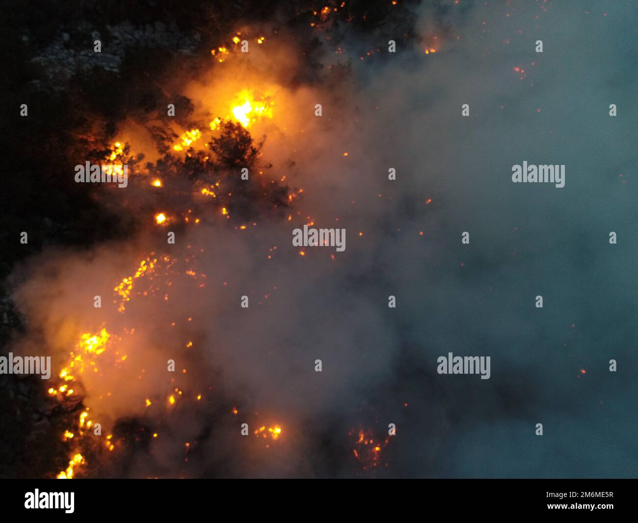 Aerial panoramic view of a forest fire at night, heavy smoke causes air ...
