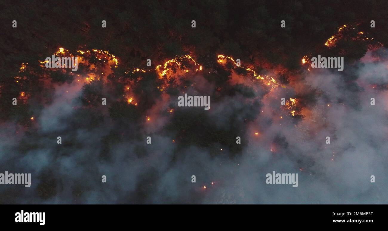 Aerial panoramic view of a forest fire at night, heavy smoke causes air ...
