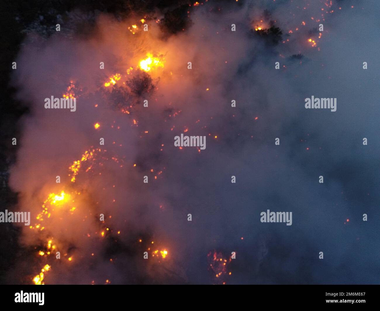 Aerial panoramic view of a forest fire at night, heavy smoke causes air ...