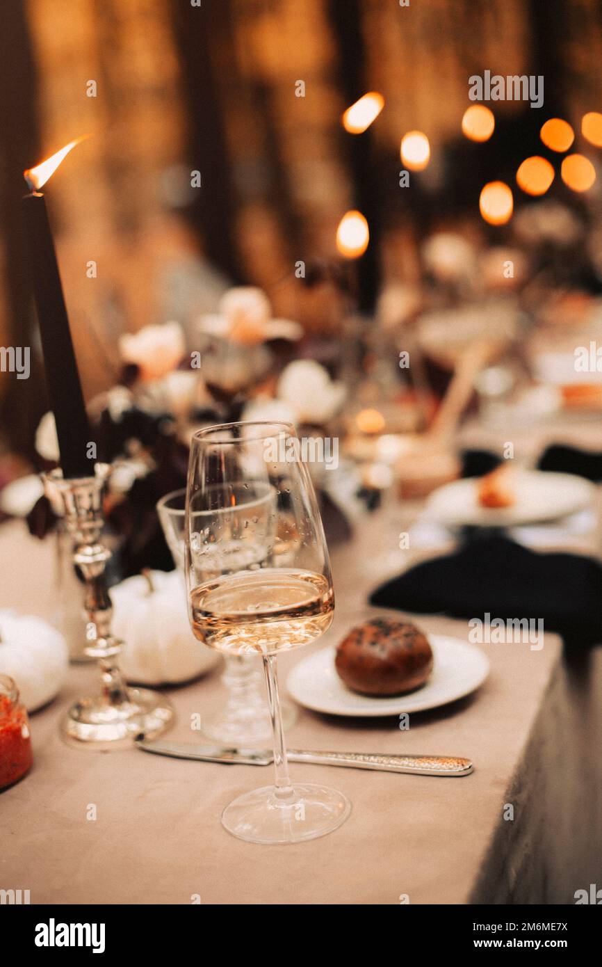 Selective focus on tall glass with white wine standing on dinner table ...