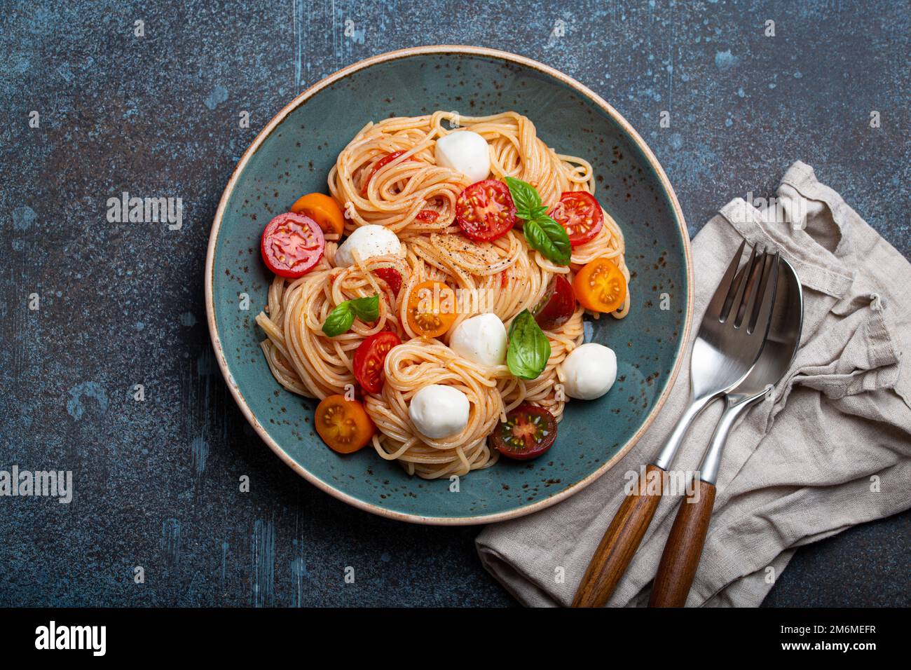 Spaghetti with mozzarella, colourful cherry tomatoes, fresh basil on ...