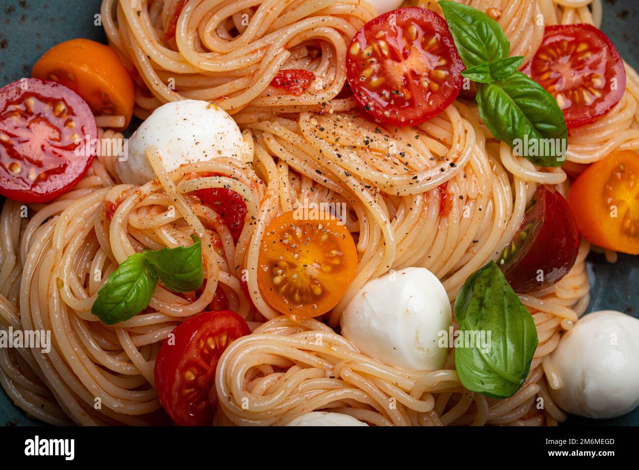 Spaghetti with mozzarella, colourful cherry tomatoes, fresh basil on ...