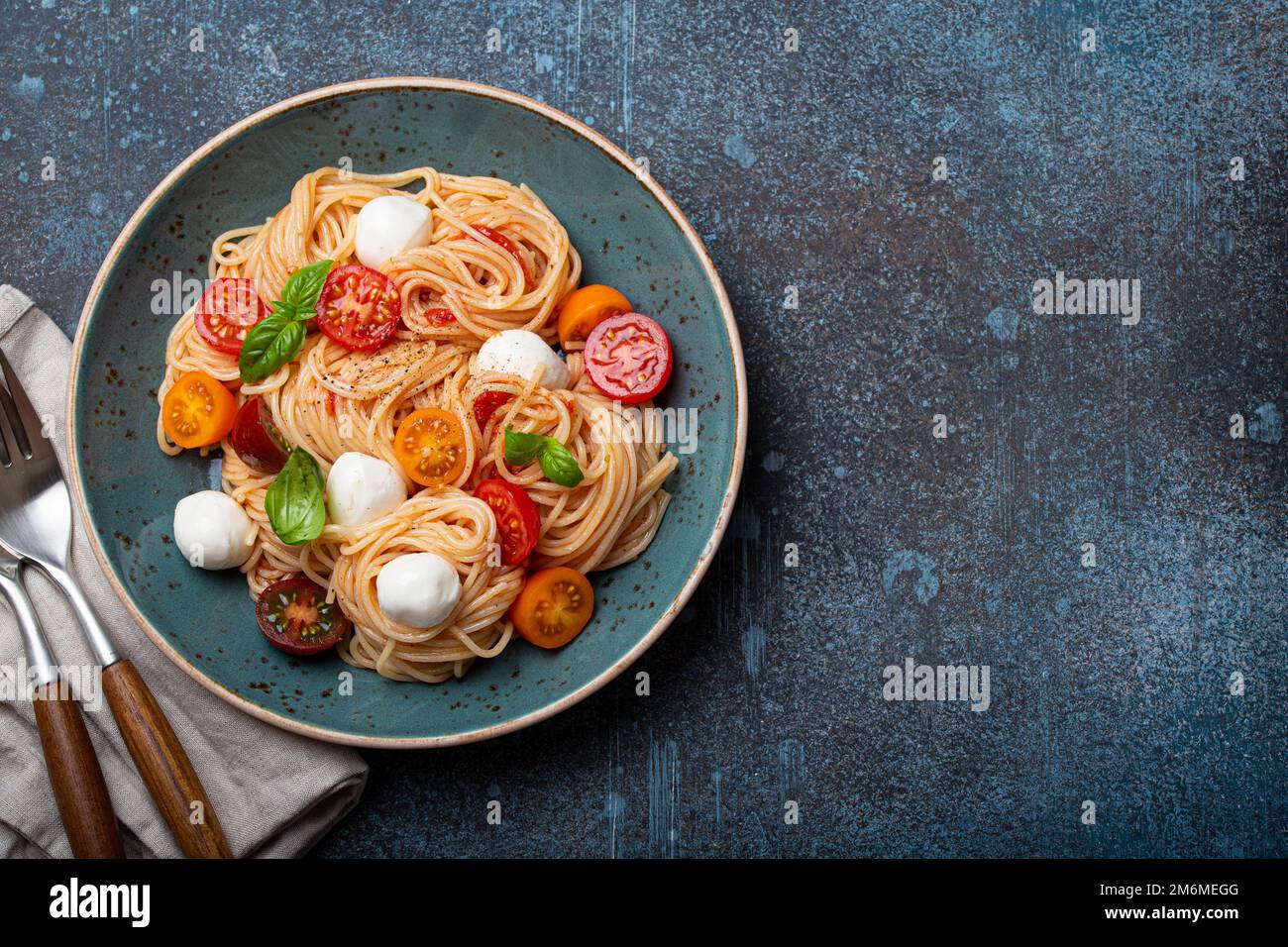 Spaghetti with mozzarella, colourful cherry tomatoes, fresh basil on ...