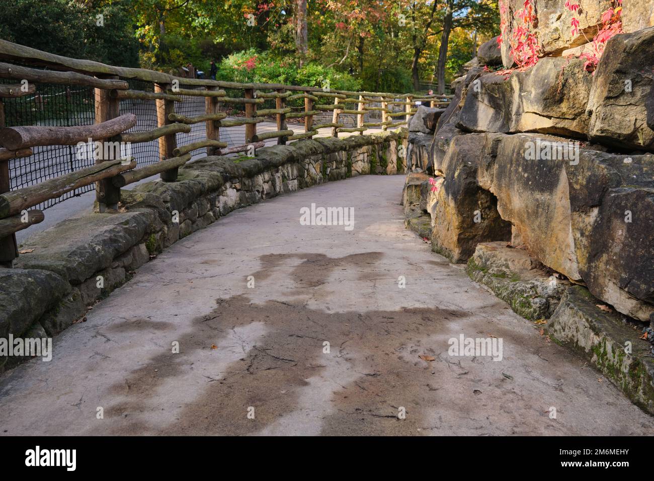 Concrete alley pathway pedestrians fenced off rock stone wall city park ...