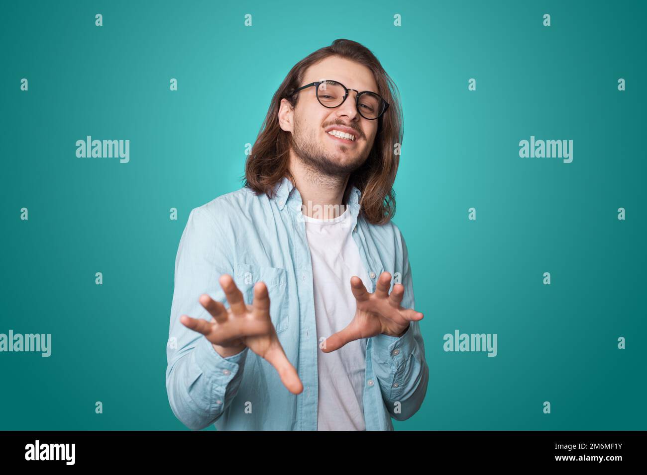 Young caucasian man doing claw gesture as cat, aggressive and funny ...