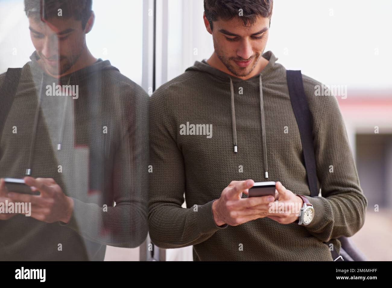 Catching up after his exam. a handsome young man using his cellphone on ...