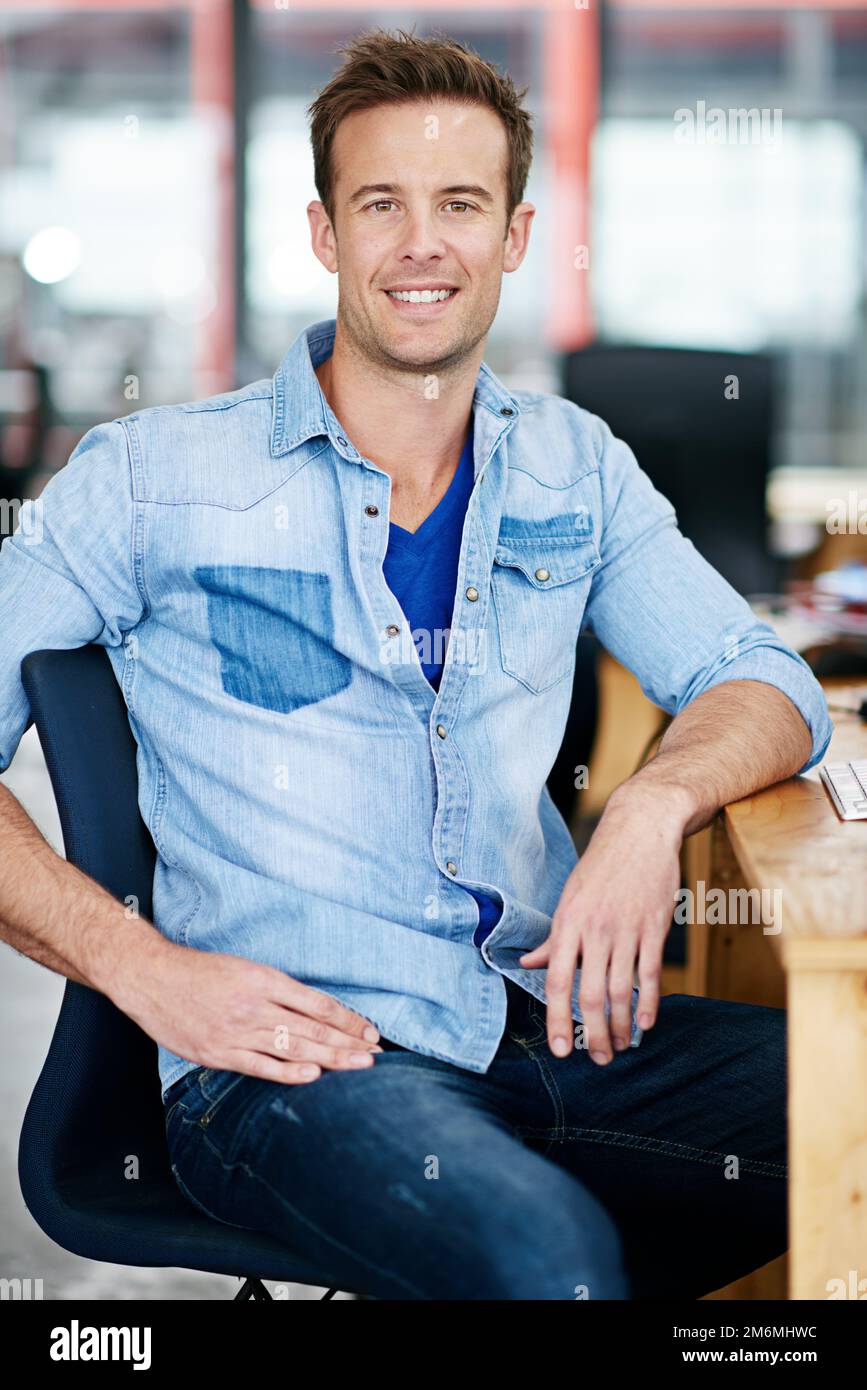 The happiest place to work. Portrait of a handsome young man sitting at ...