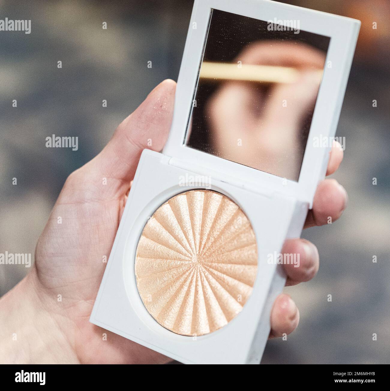 a hand holding a makeup compact with a reflection of the other hand in ...