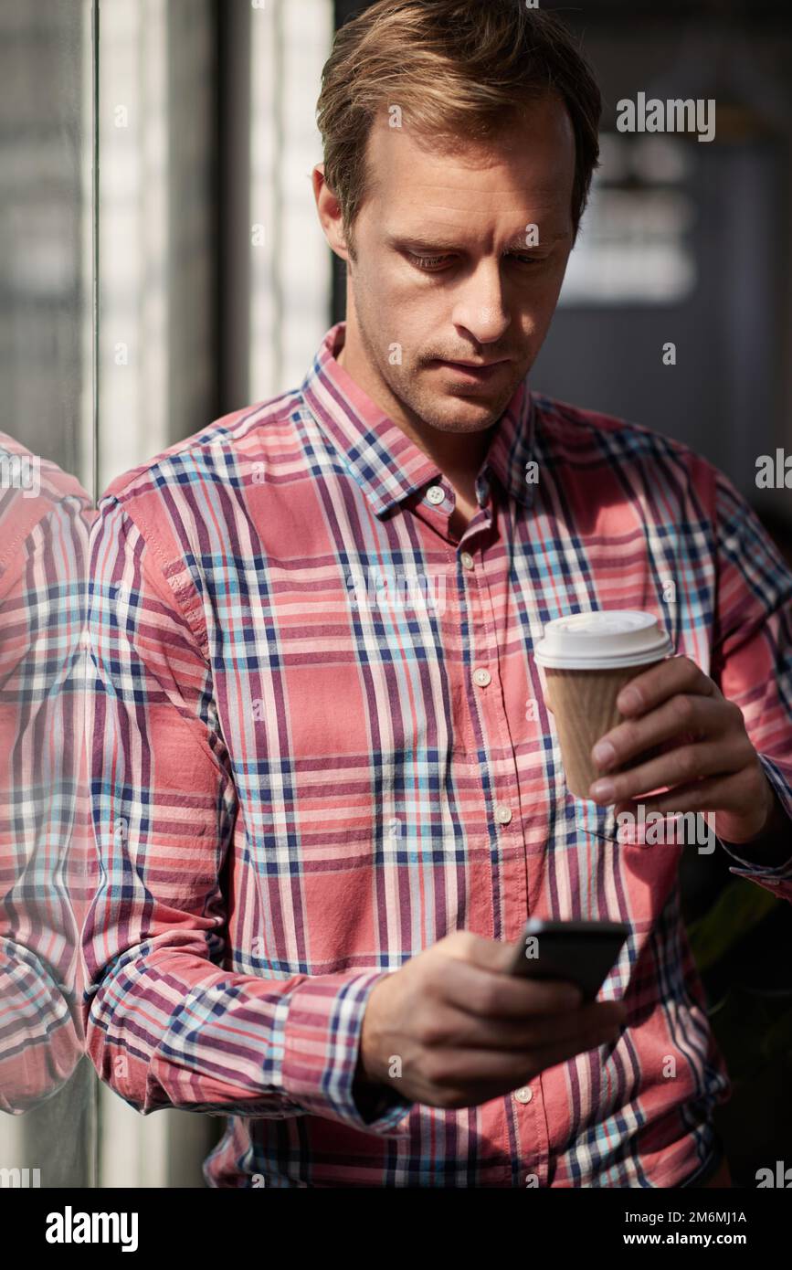 Catching a quiet moment at work. a man reading a text message while ...