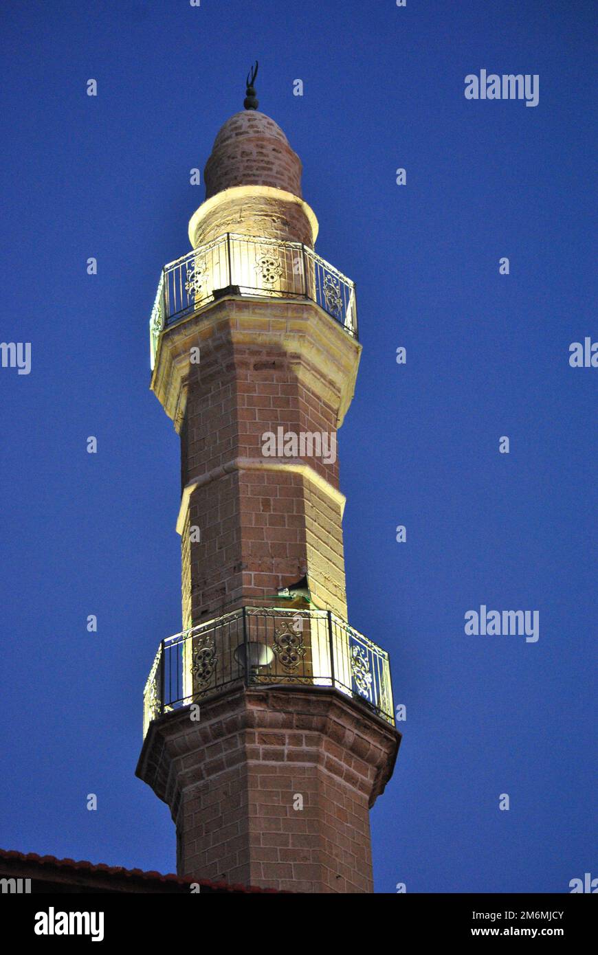 Minaret of a mosque at night with lights on it, over dark evening sky ...