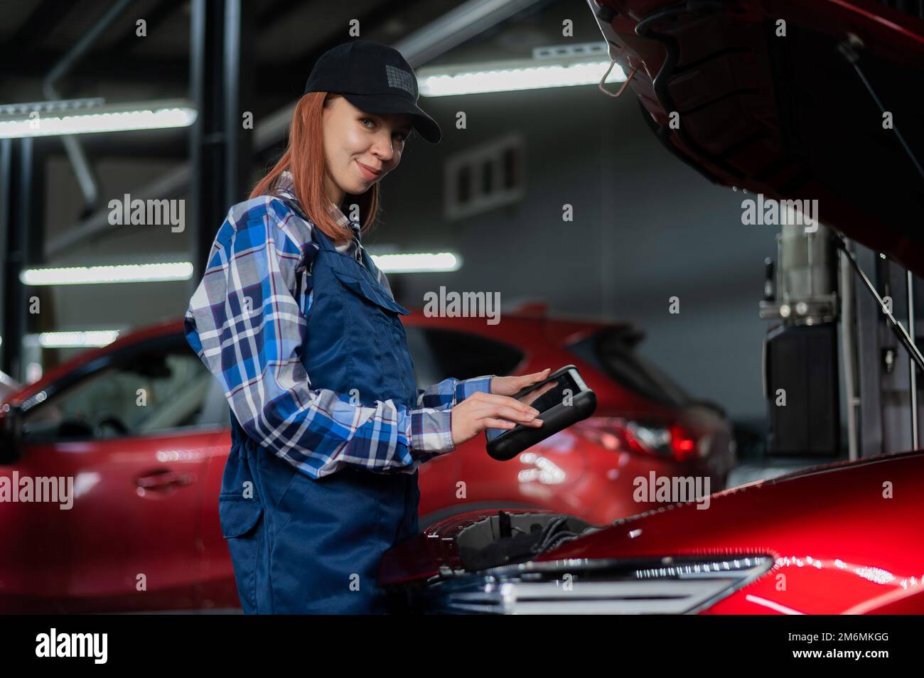 Caucasian female auto mechanic uses a special computer to diagnose ...