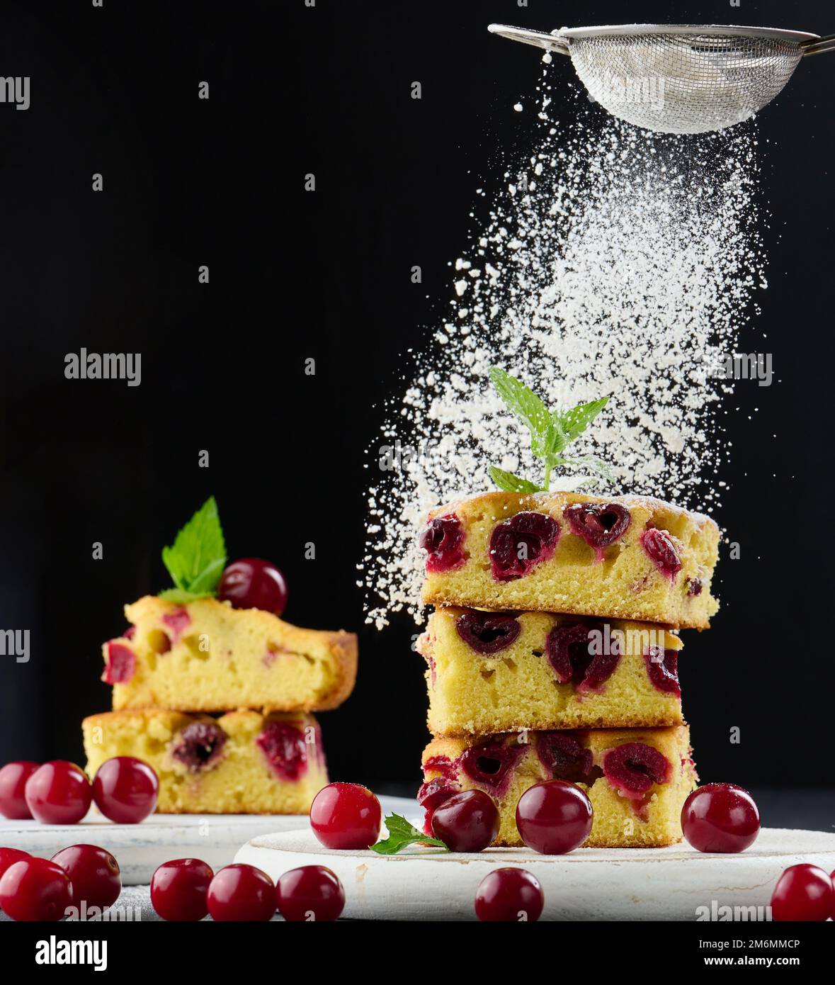 Baked sponge cake with cherries sprinkled with powdered sugar, black ...