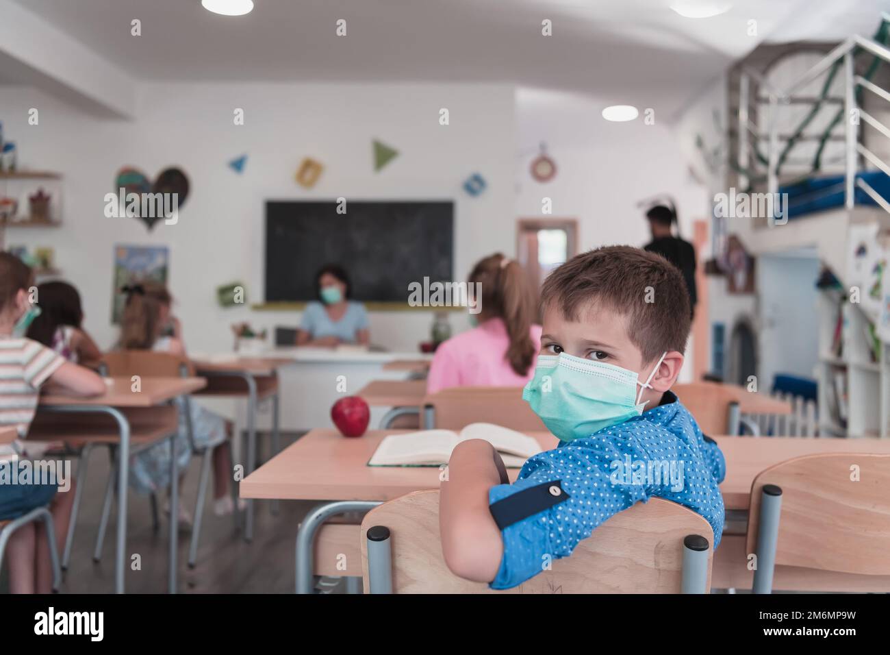 Multiracial group of kids wearing face masks working at class, writing ...