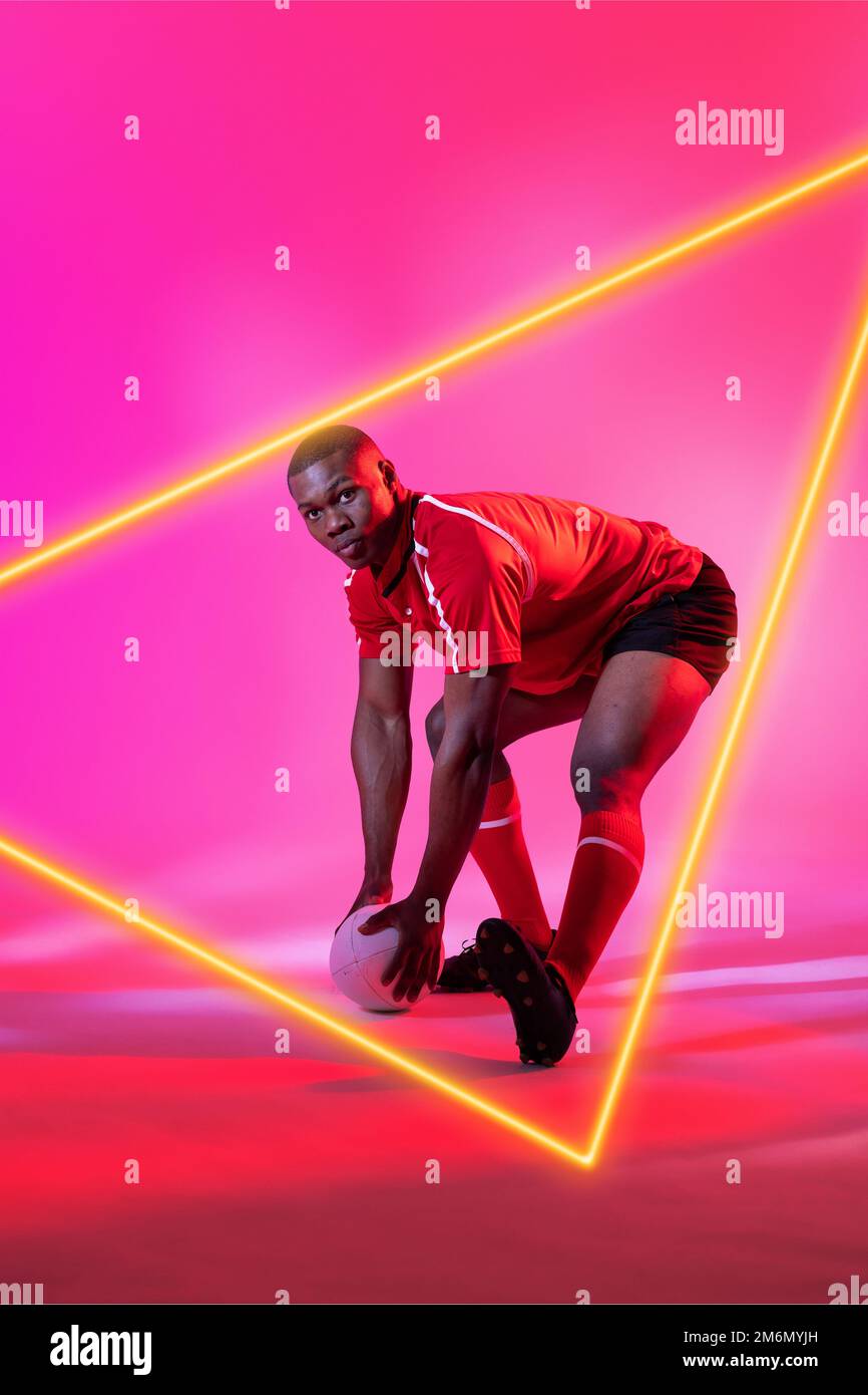 African american male player with rugby ball bending by illuminated ...