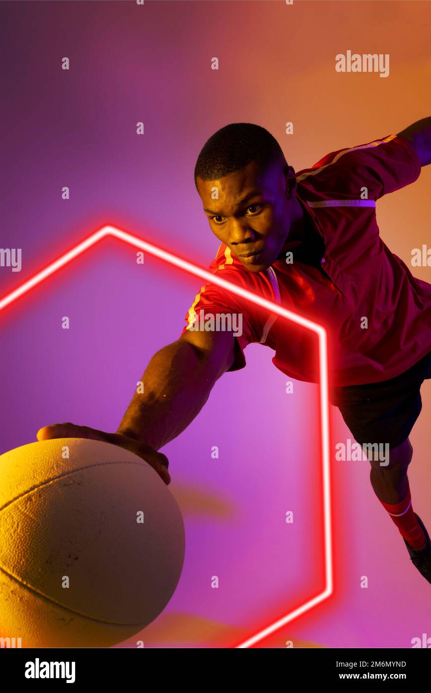 African american male rugby player catching ball by illuminated hexagon ...