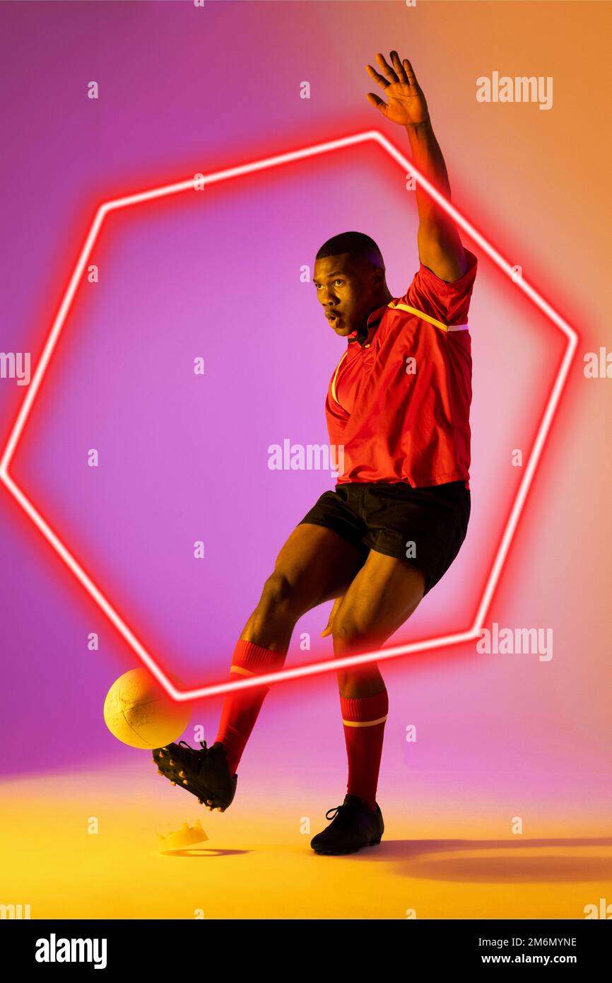 African american male rugby player kicking ball by illuminated hexagon ...