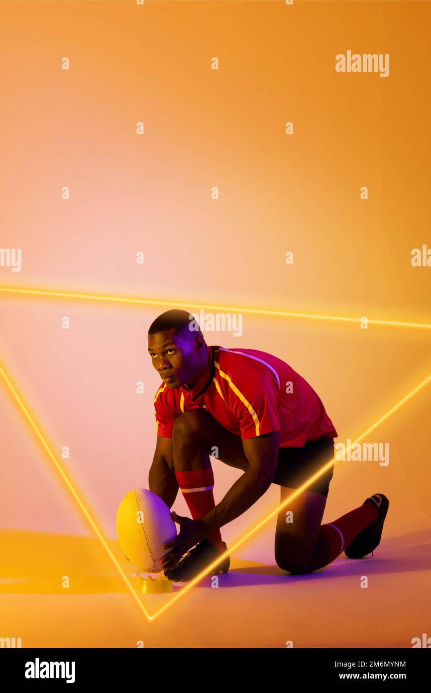 Confident african american male rugby player placing ball on stand by ...