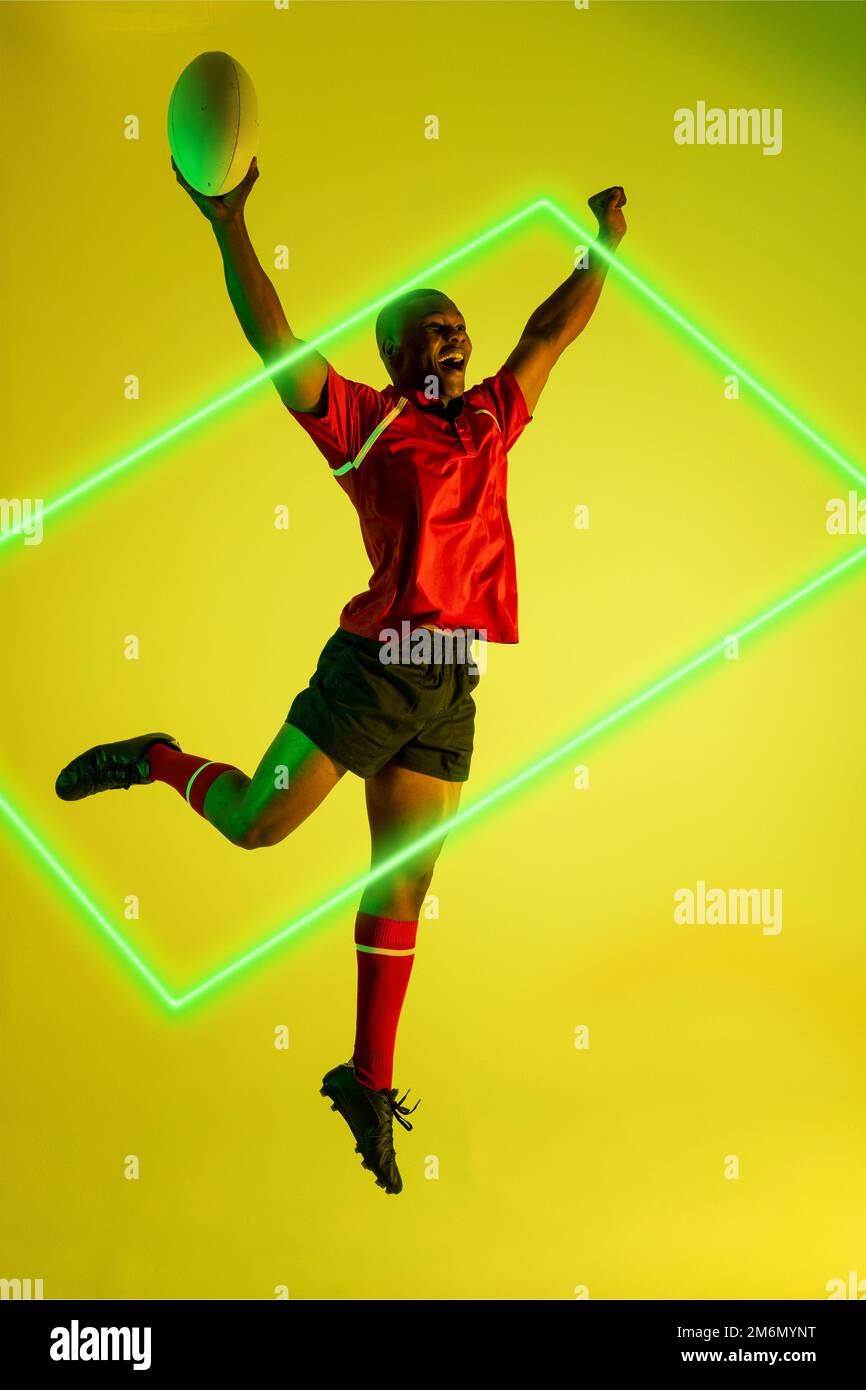 African american male player with rugby ball raising arms and jumping ...