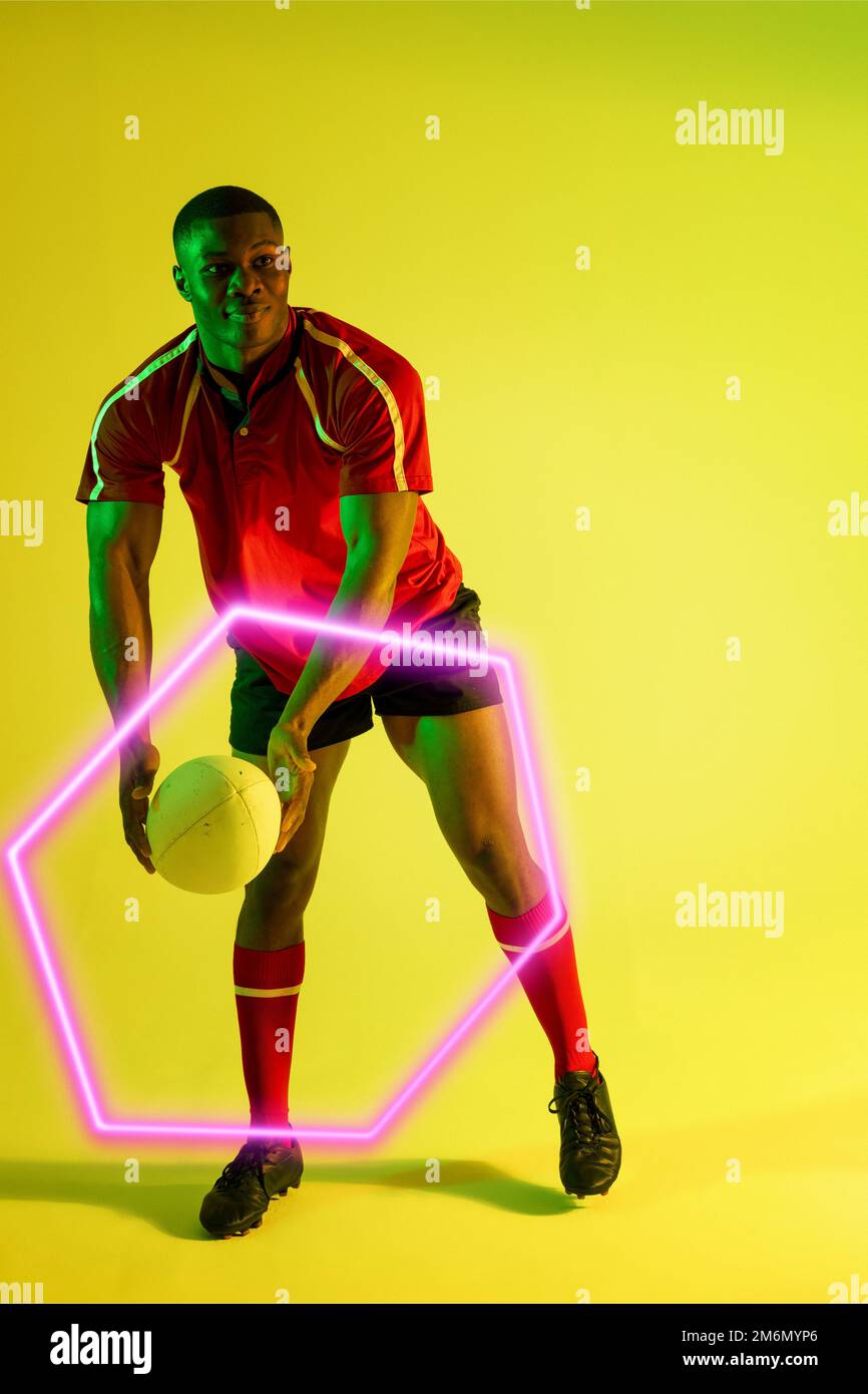 Smiling african american male player throwing rugby ball by illuminated ...