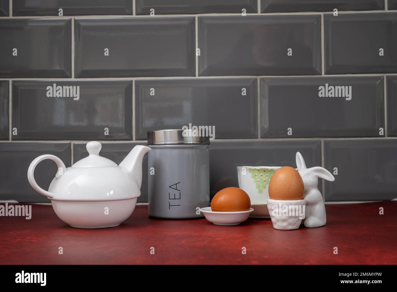 making breakfast with boiled eggs in egg cup and dish pot of tea with ...