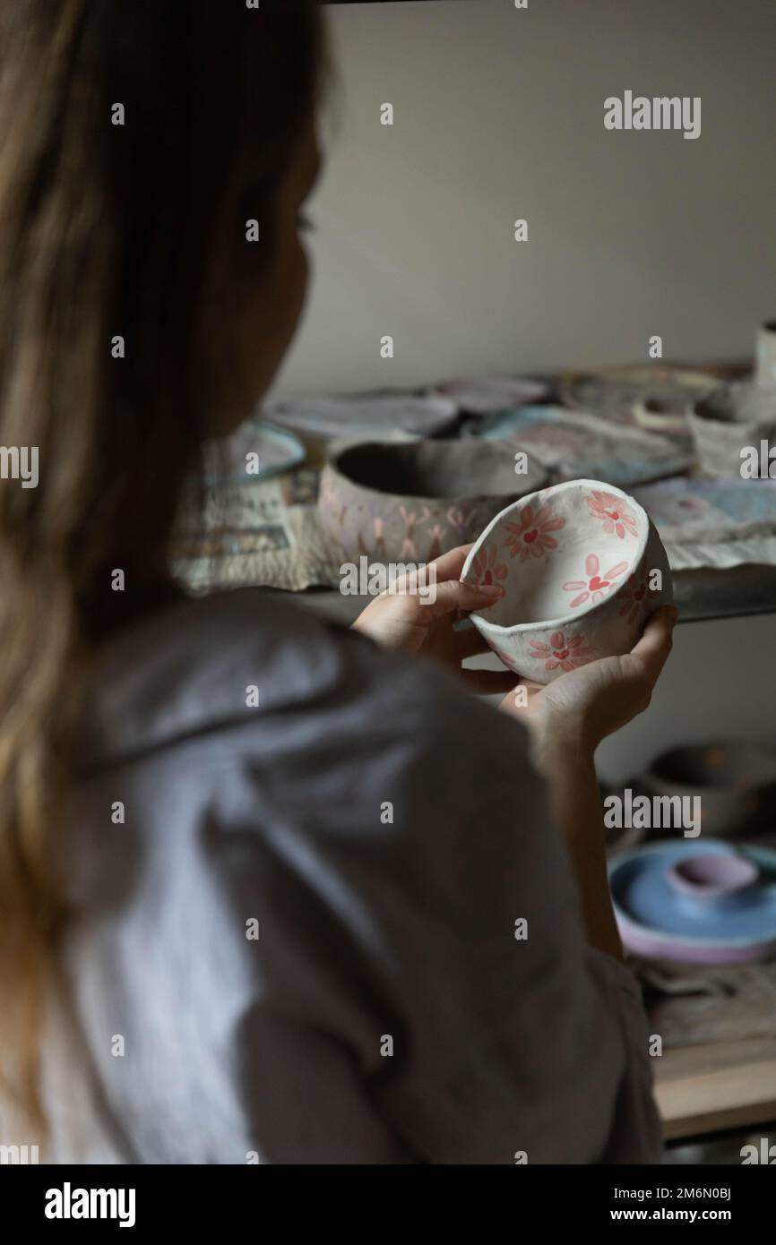 a girl from the back looks at a clay product, vertical frame, without a ...