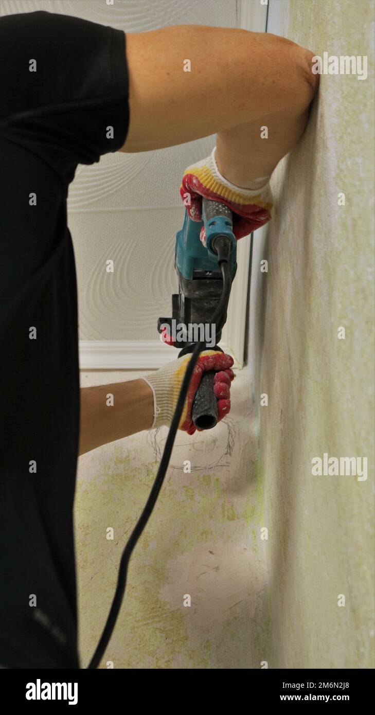 vertical image of a man in black clothes with a puncher chiseling a ...