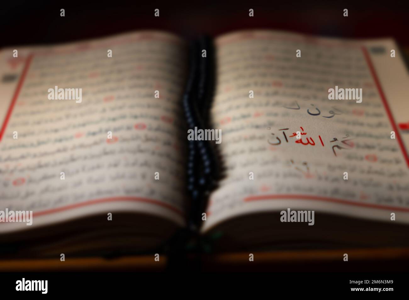 Allah text on the Holy Quran in focus. Blurry background. Ramadan or ...