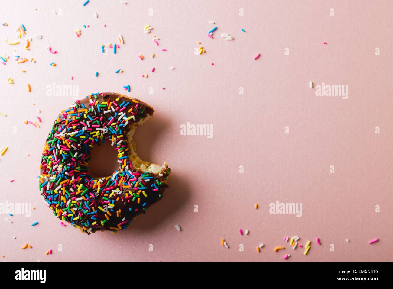 Directly above view of missing bite of chocolate donut with sprinklers ...