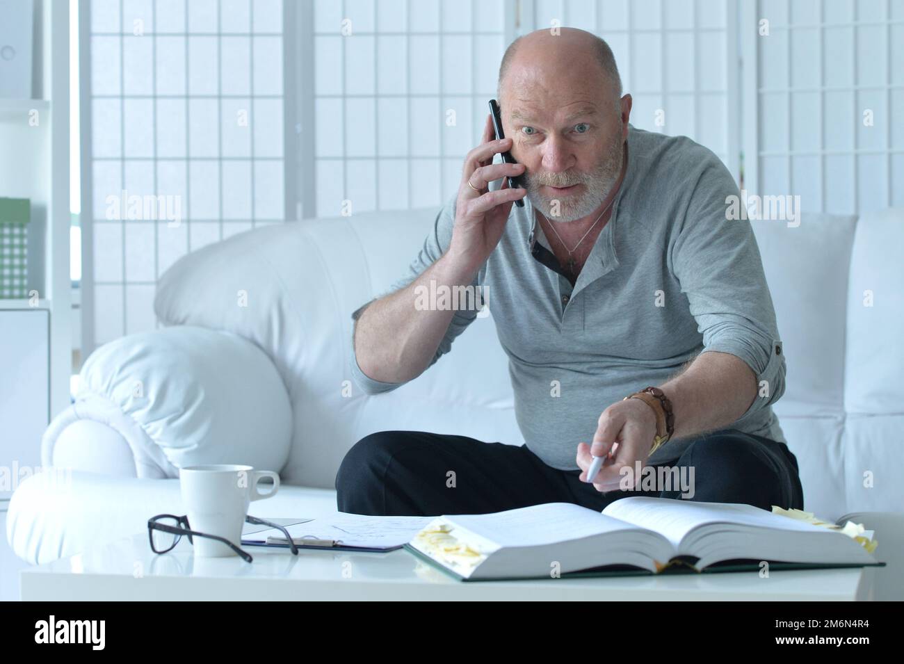 old man with book talking on phone and taking notes Stock Photo - Alamy