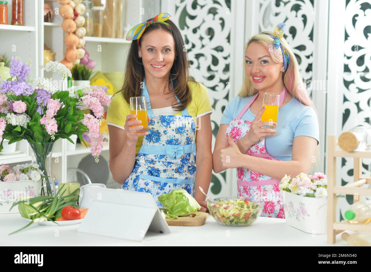 Two beautiful young women cooking together in kitchen Stock Photo - Alamy
