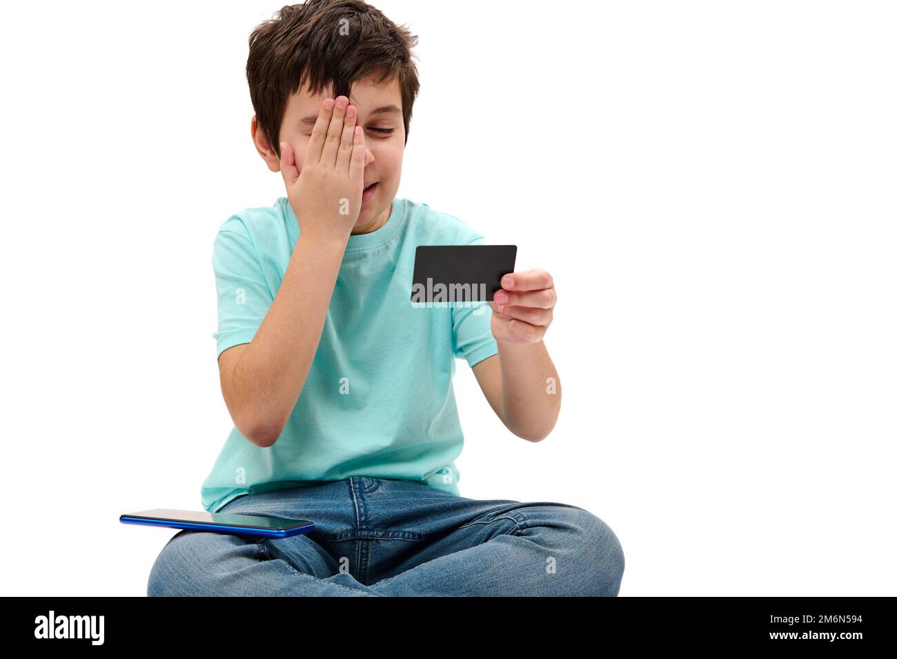 Caucasian teenage boy looking at credit card, expressing ...