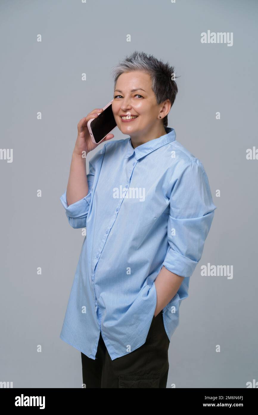 Mature woman with grey hair talking holding smartphone at her ear ...