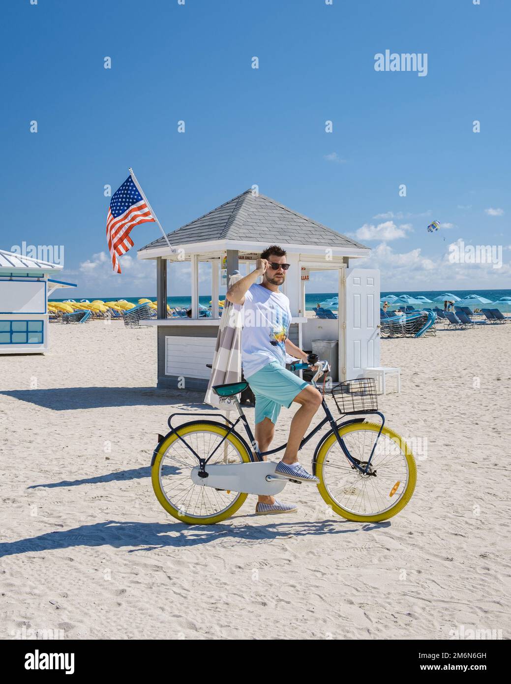 Young men in a swim short on the beach Miami with a bicycle, colorful ...