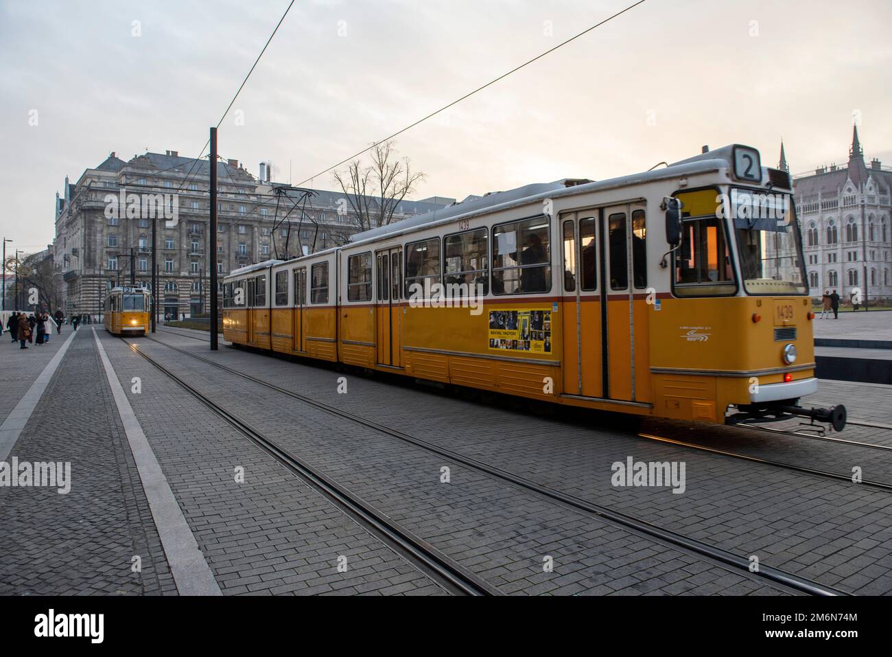 Iconic yellow trams passing the Parliament of Budapest at Kossuth ...