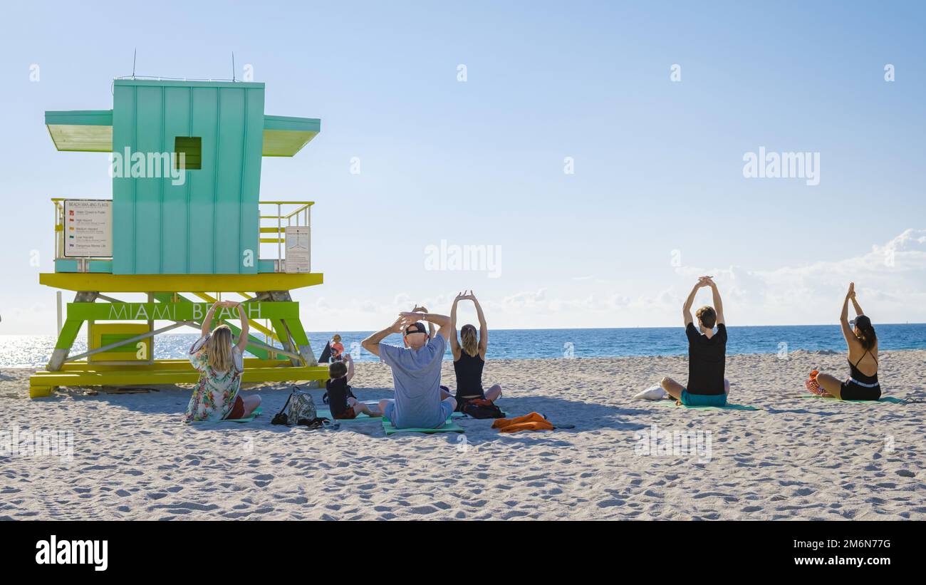 Group of people doing yoga during sunrise on the beach at Miami Florida ...