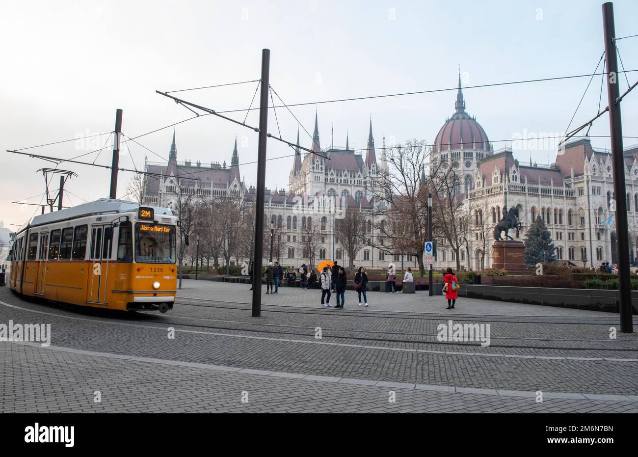 An iconic yellow tram passing the Parliament of Budapest at Kossuth ...
