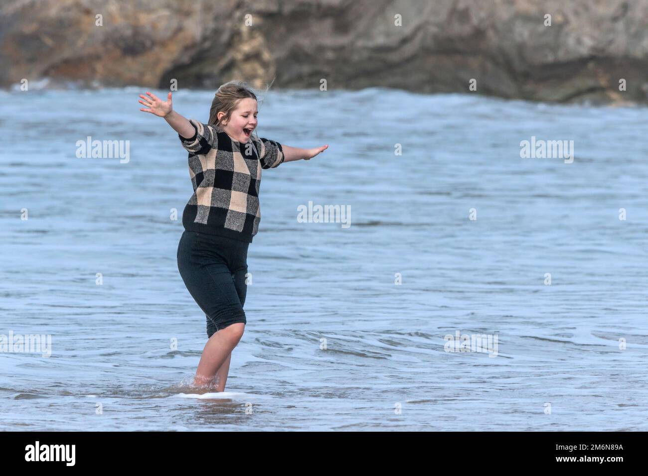 An excited child enjoying paddling in the sea at Fistral in Newquay in ...