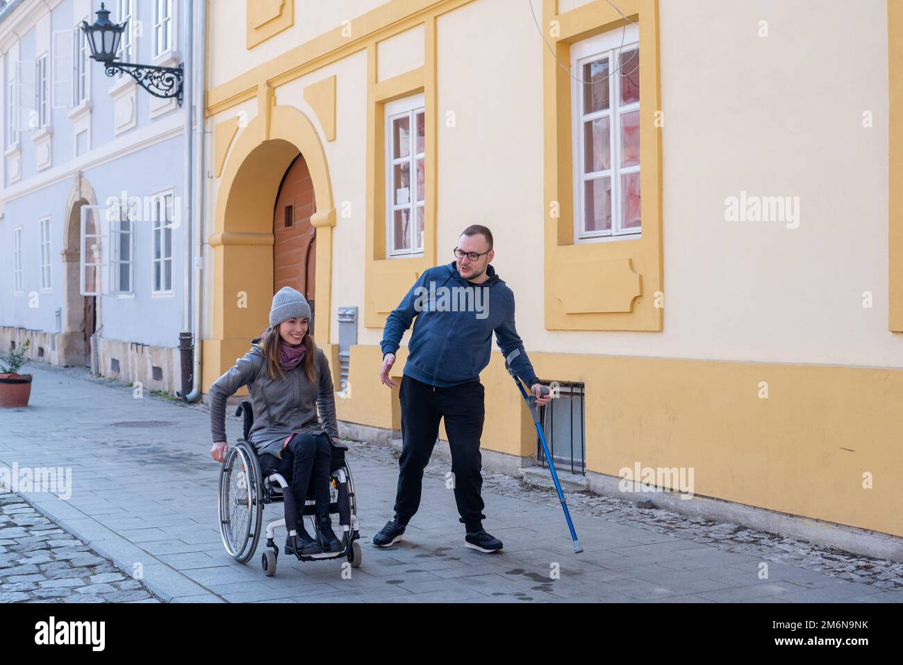 Friends with a disability. Woman in a wheelchair and man with a walking ...