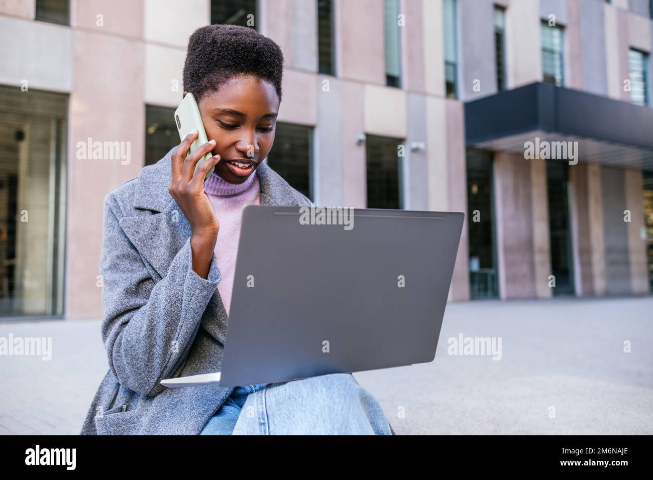 African American woman in stylish clothes answering phone call while ...