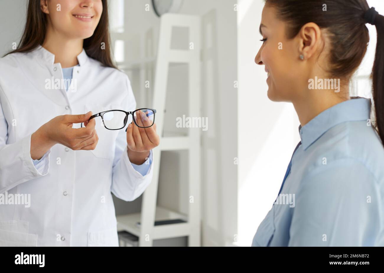 Happy ophthalmologist, optician or optometrist giving new eyeglasses to ...