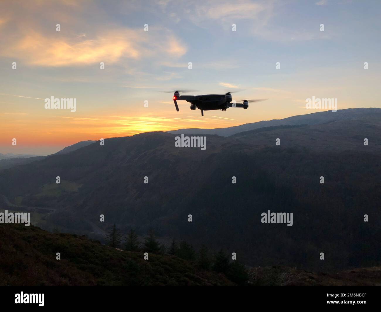 A drone flying over the mountain at sunset Stock Photo - Alamy