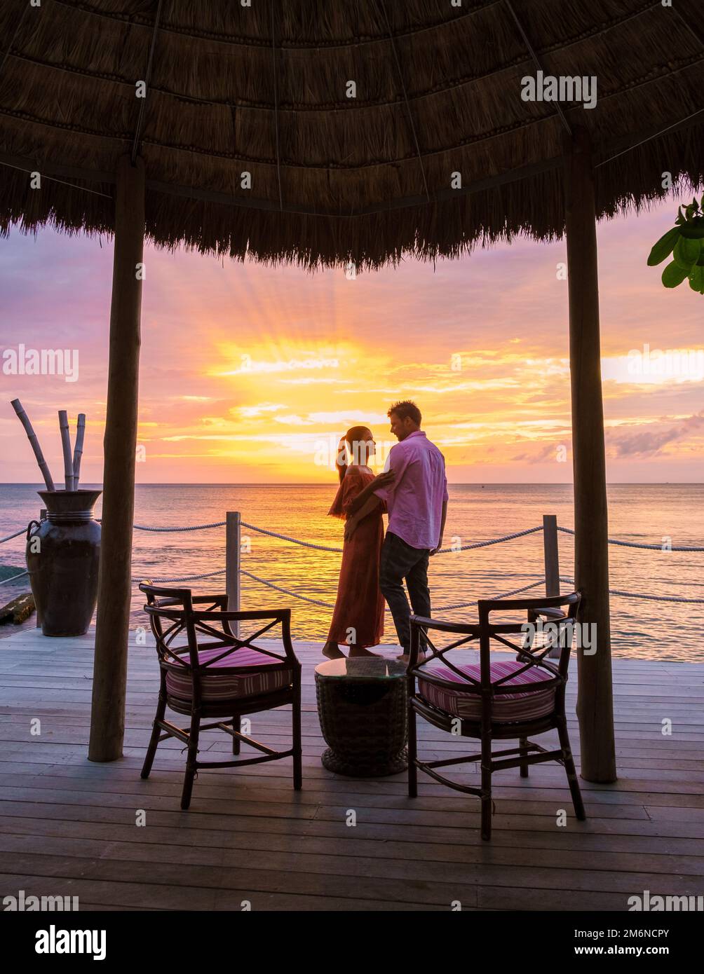 Couple drinking cocktails during sunset at the tropical beach of Saint ...
