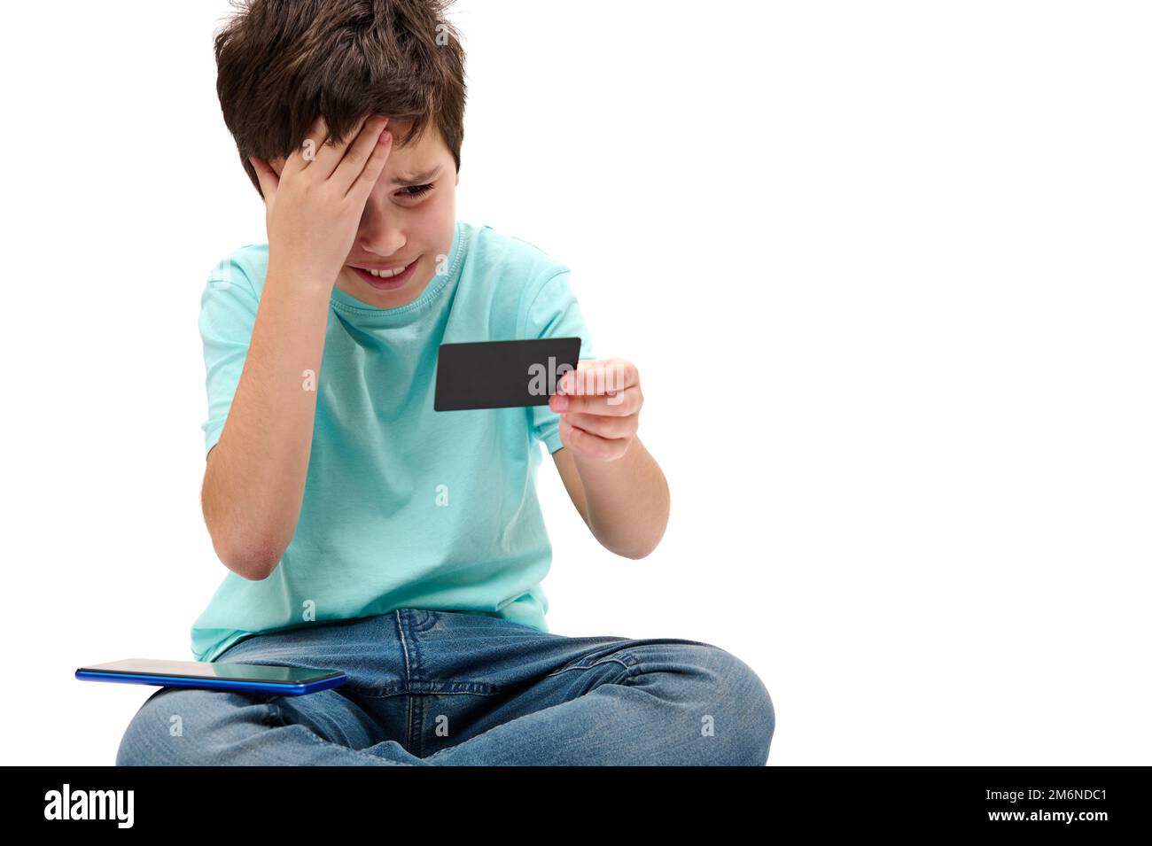 Dissatisfied teenage boy looking at credit card, expressing ...